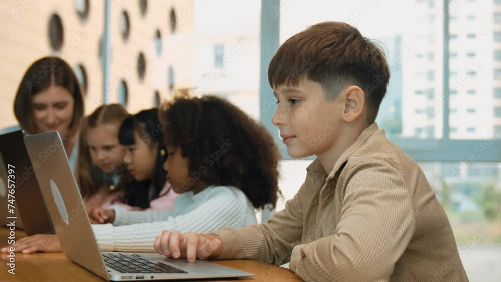 Boy looking at camera with multicultural friend learning prompt at STEM technology class ...