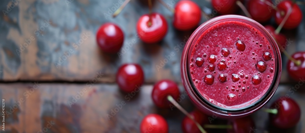 Foto Stock A glass filled with a vibrant red cherry smoothie sits on a ...