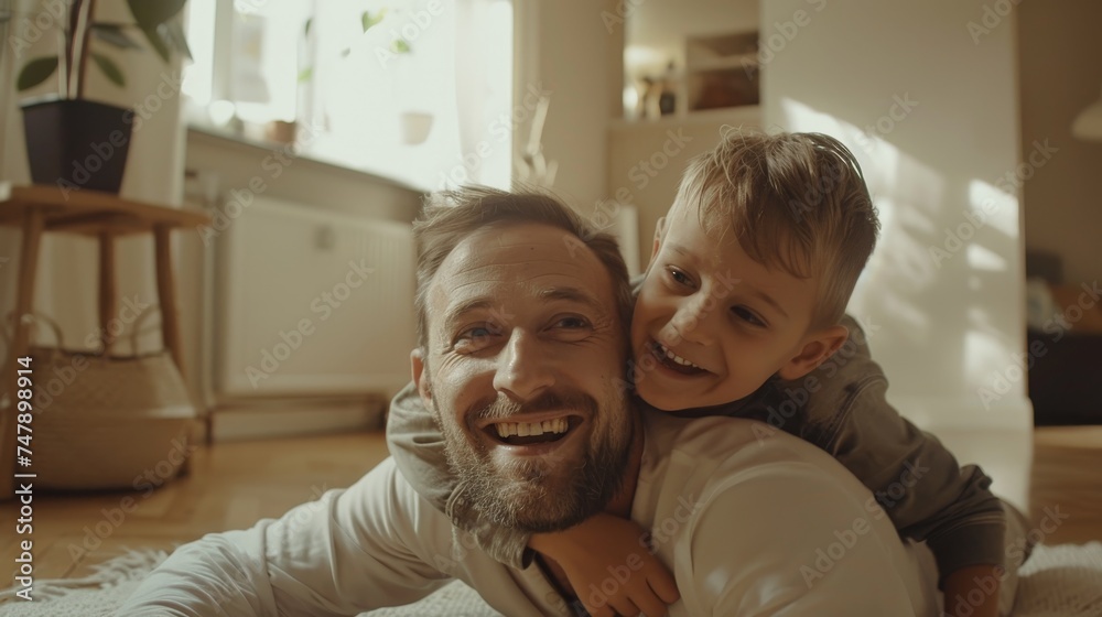 Joyful father and son having fun on the floor, dad lying on the floor ...