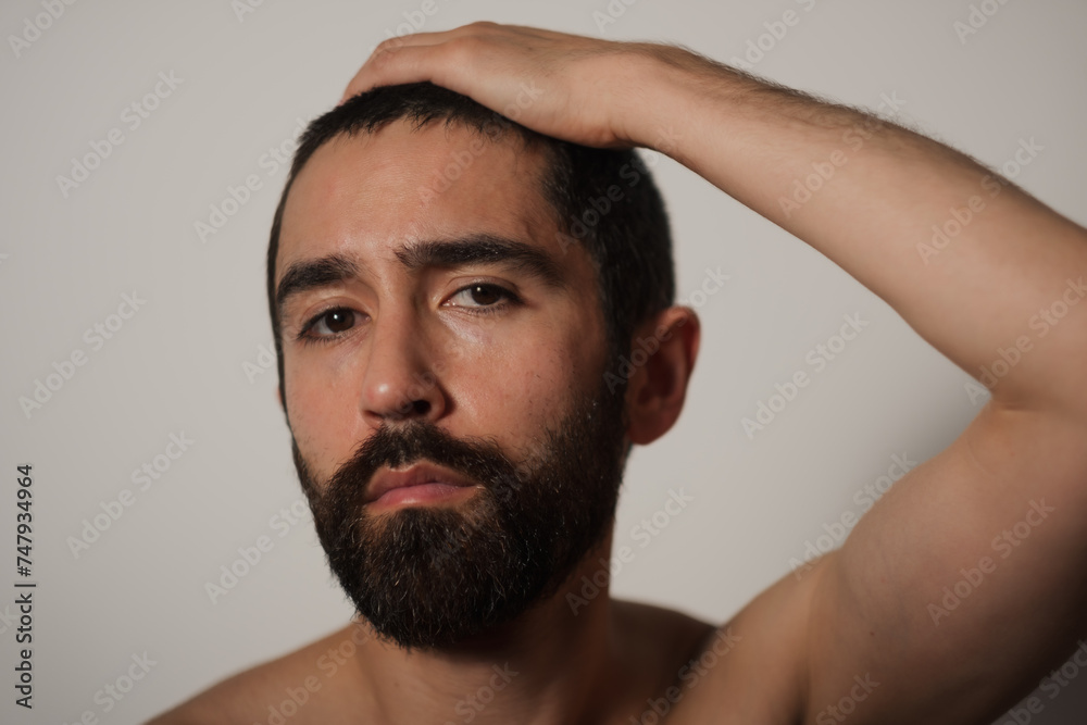 With his brow slightly furrowed, a man lifts his arm up and puts his ...