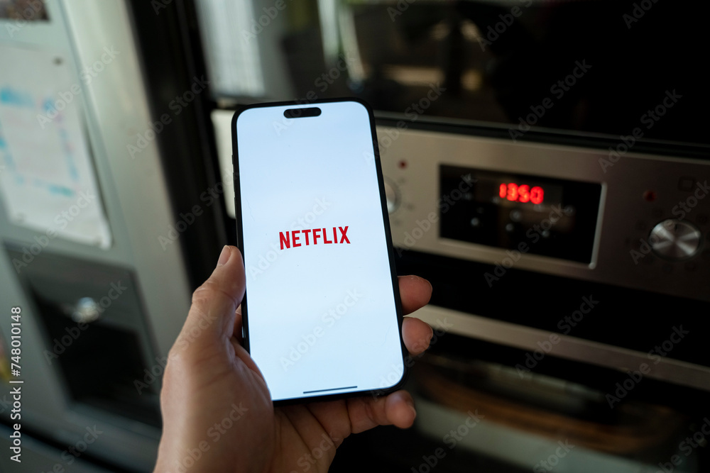 Man holding an iPhone 14 Pro Max smartphone with Netflix app in his ...