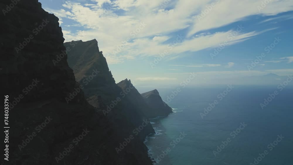 A cliff falling into the blue ocean. Looks like Dragon's Tail. A wall ...
