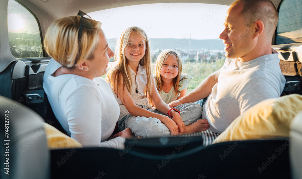 Portrait of happy smiling little sisters. Happy young couple with two daughters inside the car ...
