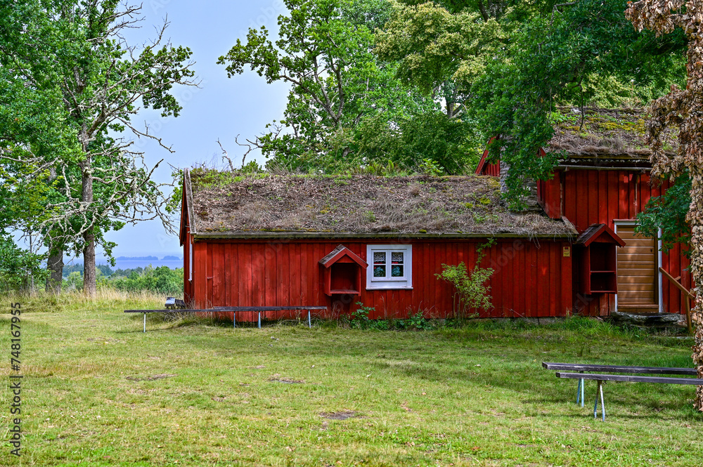 typical, traditional red Swedish house, wooden house with a mossy roof ...