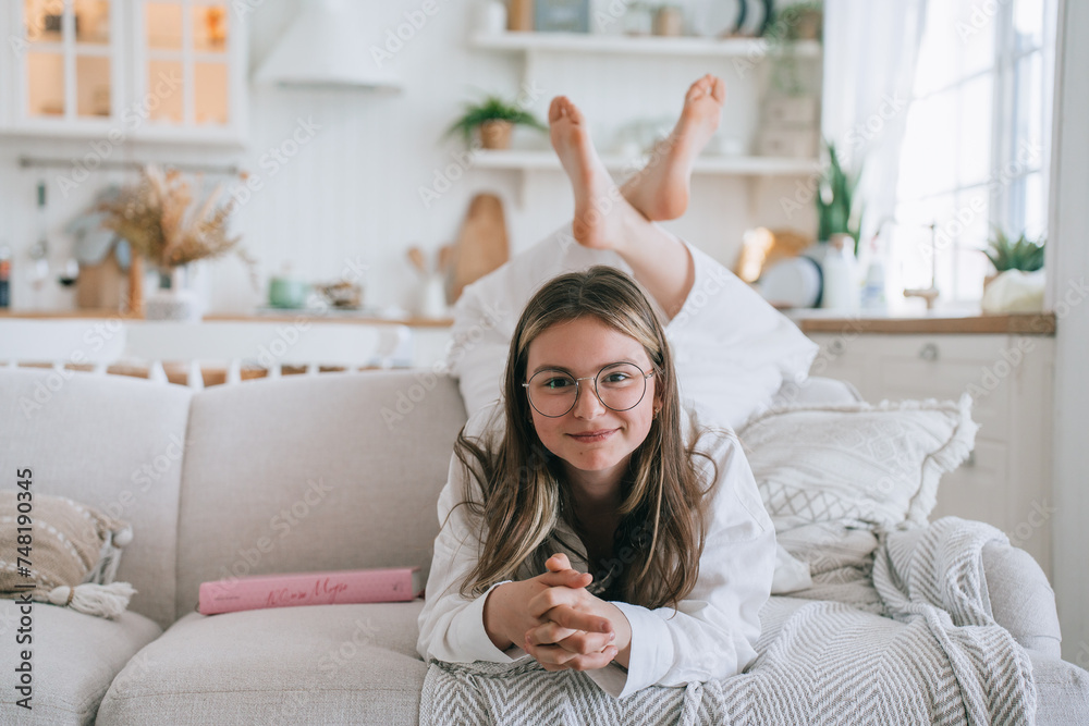 Cheerful girl lying on couch, playful pose in a cozy living room ...