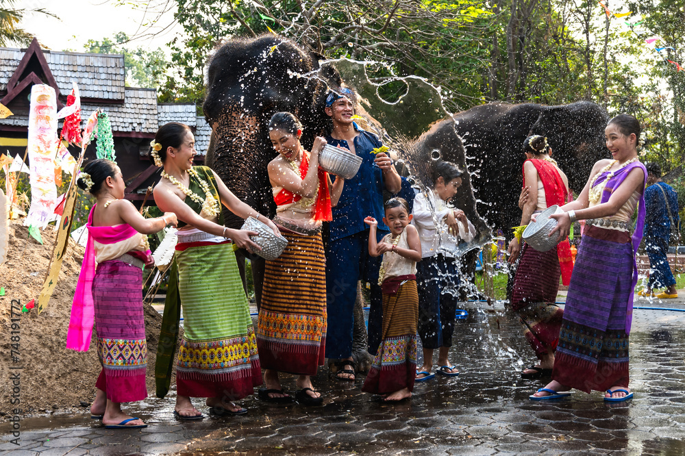 Group of Thai people and children in traditional Thai dresses splashing ...