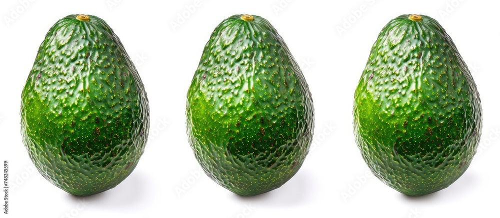 Three green avocados are arranged neatly next to each other on a plain ...