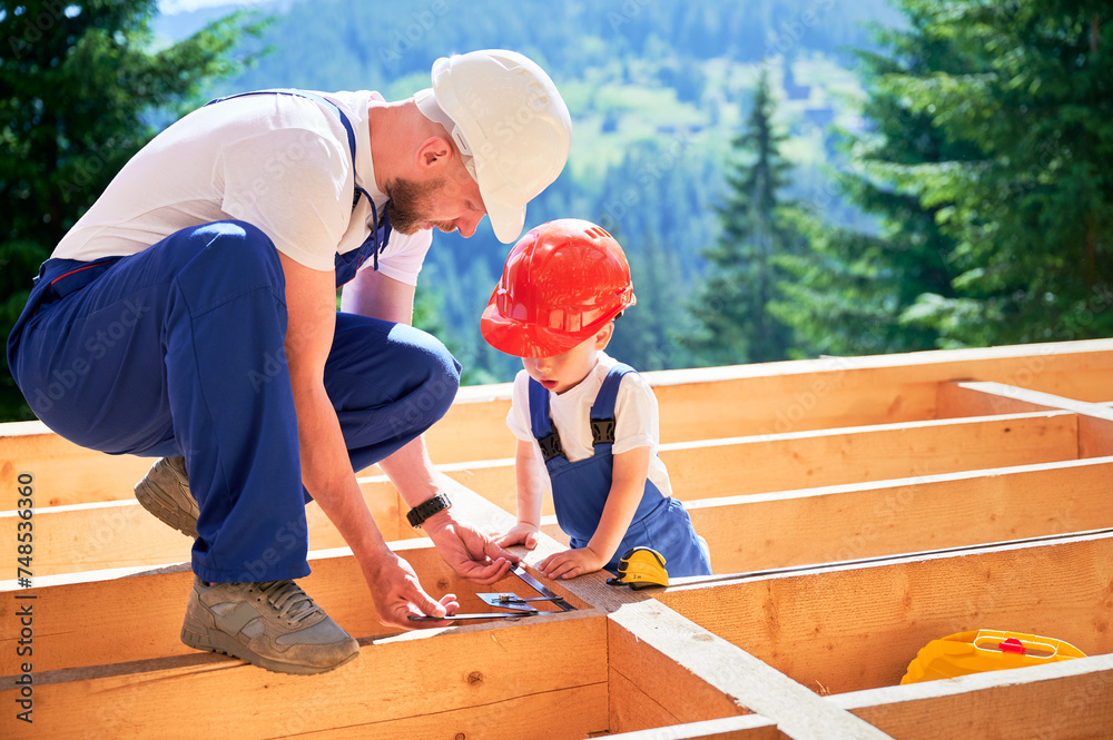 Father with toddler son building wooden frame house. Male builder ...