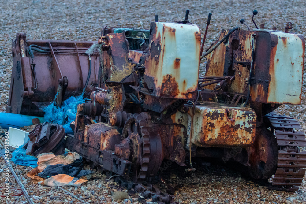 Abandoned bulldozer on shingle beach rusting away along the British ...