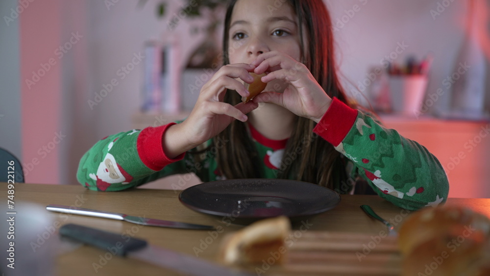 Little girl eating piece of bread seated at table wearing pajamas. 8 ...