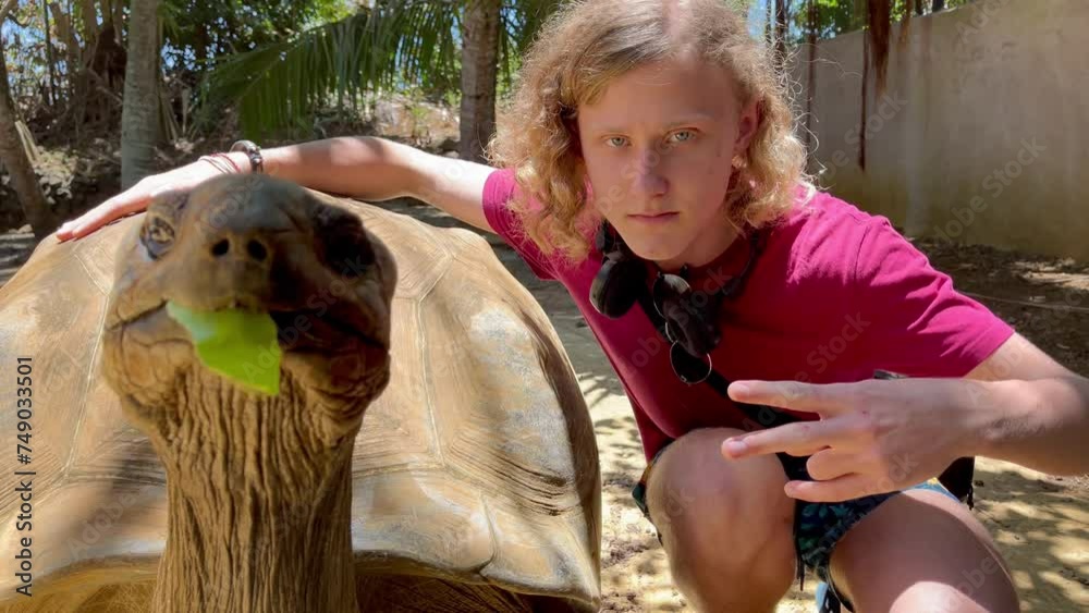 Tourist boy posing for photo with Aldabra giant tortoise endemic ...