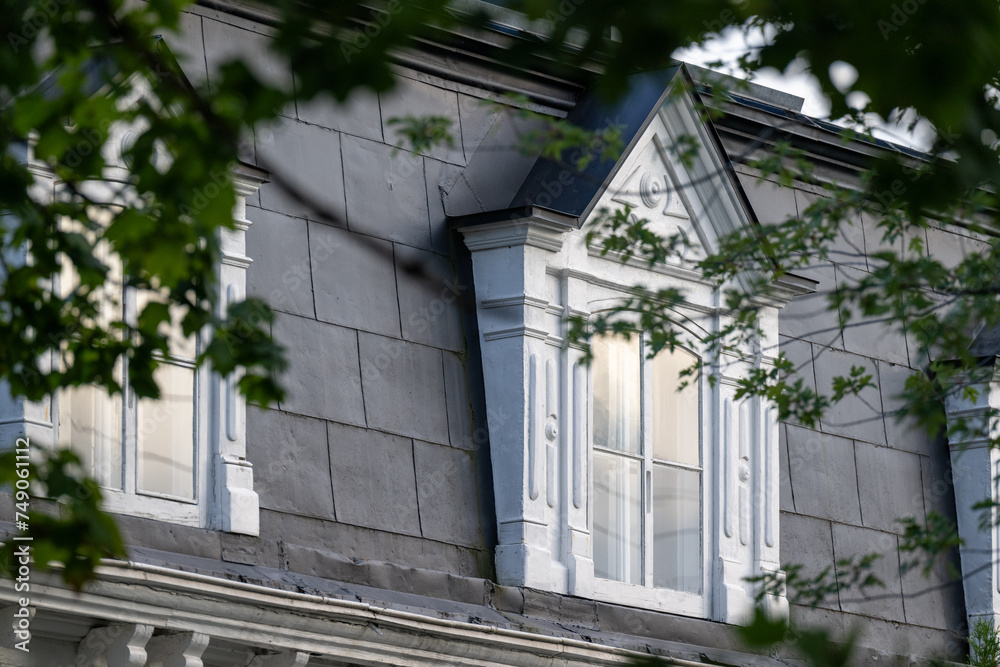 The upper storey of a historic building with a grey mansard tin roof ...