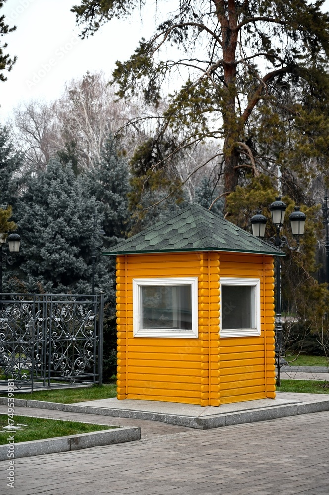 Yellow security guard booth with fir and pine trees in the background ...