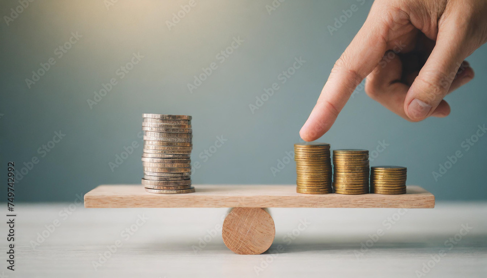 Finger rests on one side of wooden seesaw, opposite side holds coin ...