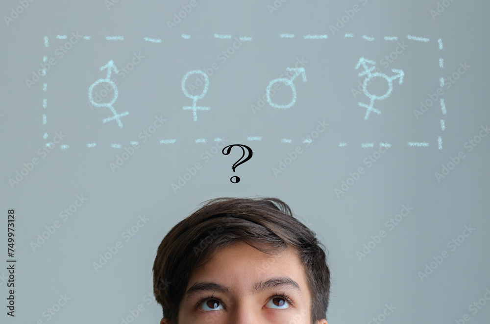 Gender confusion in teenager. A teen boy look up at gender symbols of ...