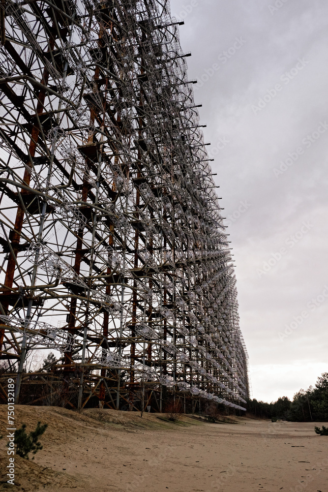 Amidst dry grass, an intricate metal tower extends into the sky ...
