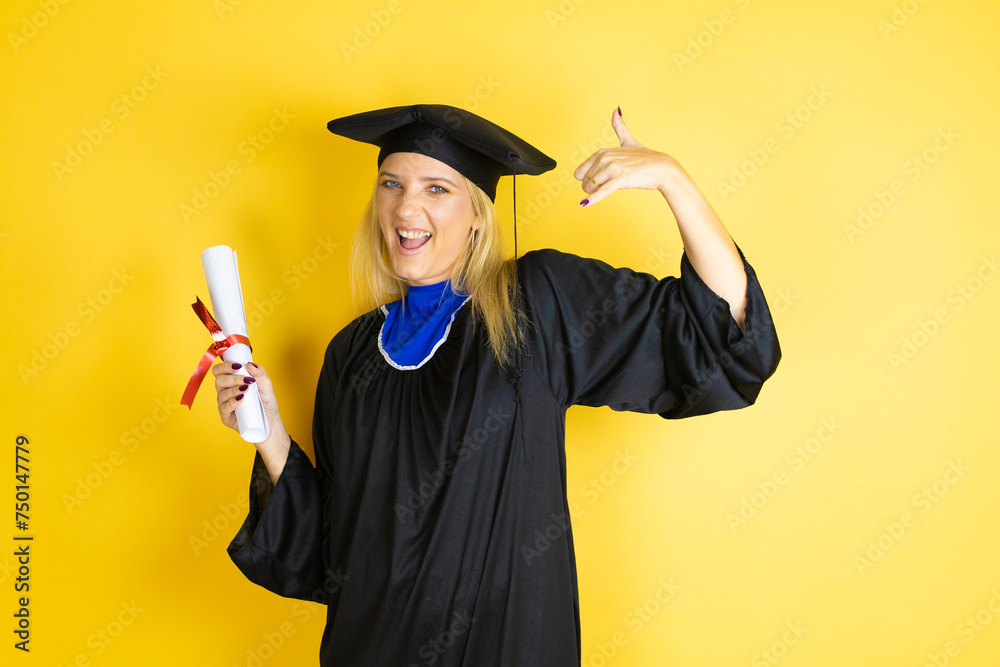 Beautiful blonde young woman wearing graduation cap and ceremony robe ...