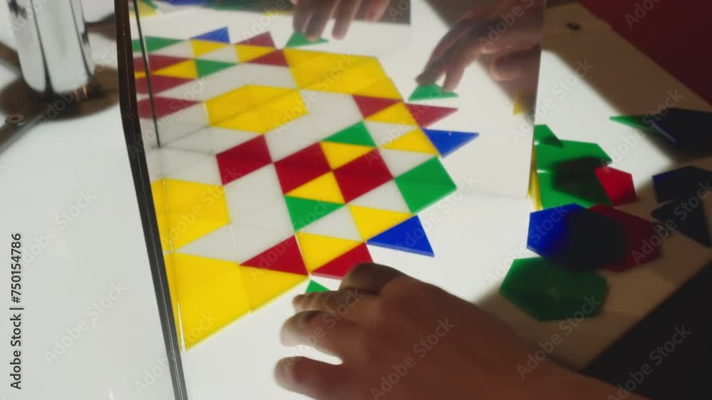 Close-up hands assemble a mosaic of colored pieces on a special table ...