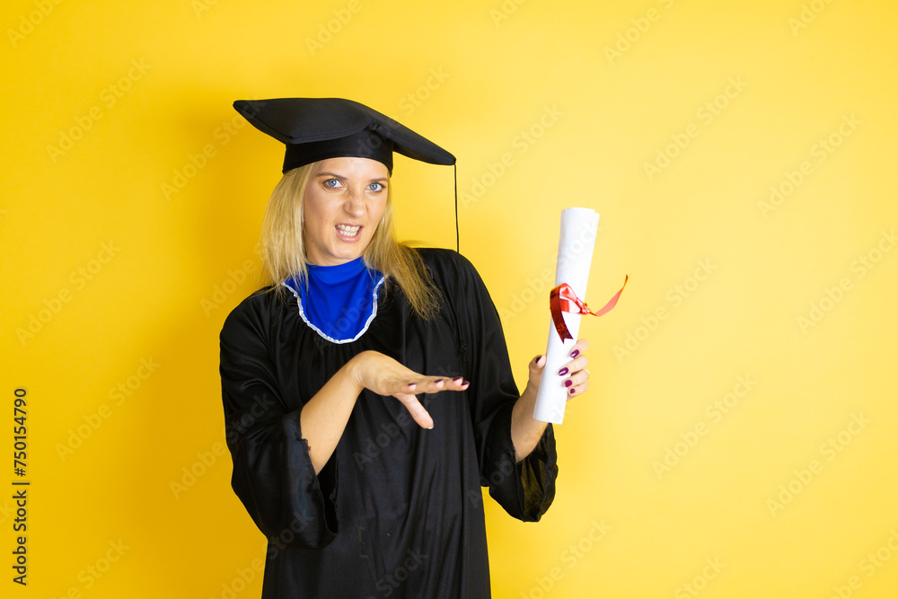 Beautiful blonde young woman wearing graduation cap and ceremony robe ...