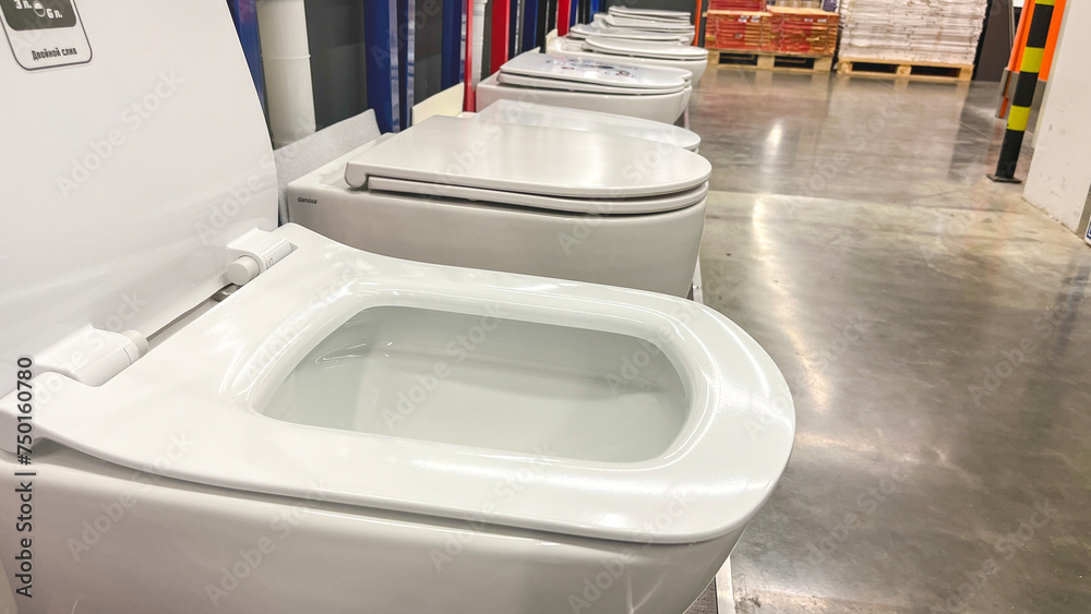 Plumbing, white toilets standing in a row in a store. Close-up ...