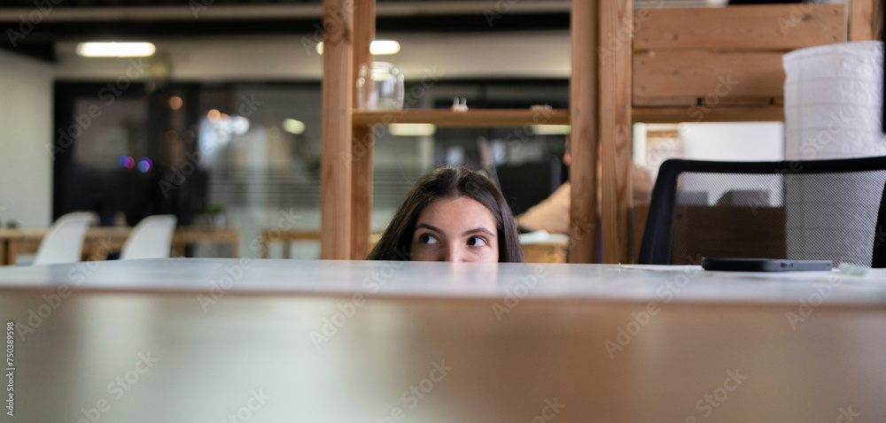 Office Worker Sneaking a Peek Above Laptop in a Modern Workspace During ...