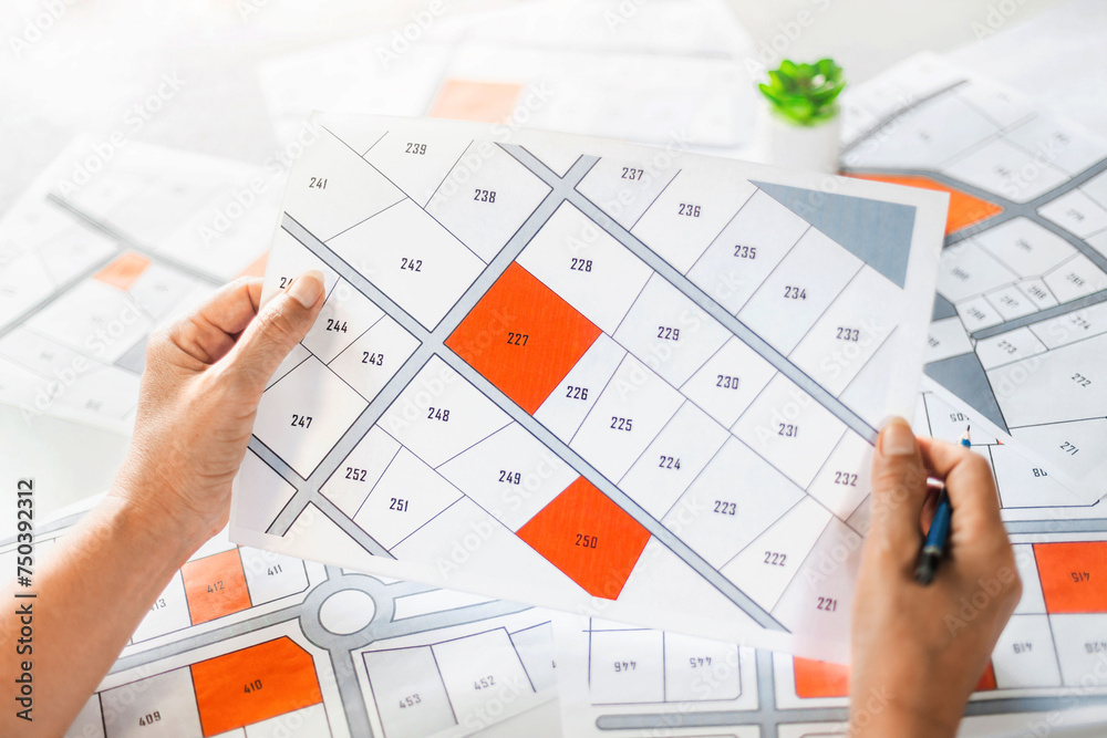 Woman holding a cadastral map looking at lots of lands. Land plot ...