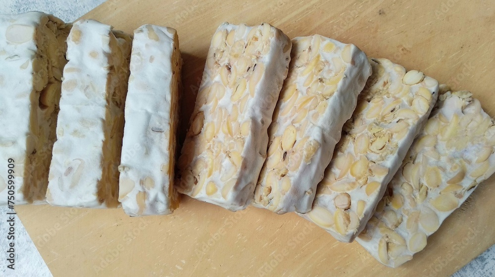 Raw tempe in slices on wooden chopping board. Raw Tempeh, traditional ...