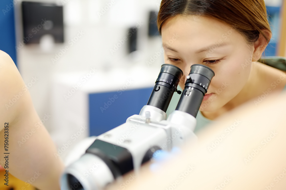 Gynecologist examines a patient using microscope in a gynecological ...