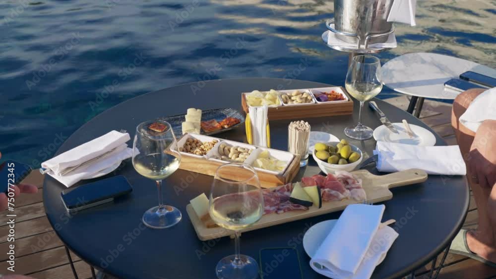 Friends having aperitif time on the swimming pool side, people sitting ...