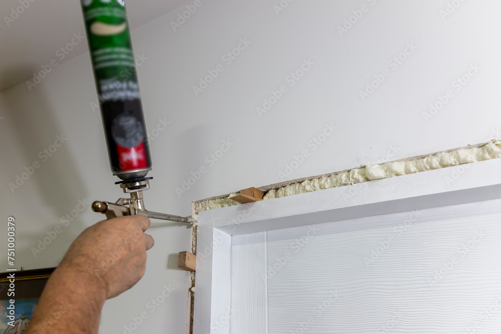 A worker's hand installing a door frame of an interior door with a ...