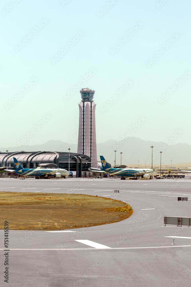 Muscat airport control tower. Oman Air planes at the boarding gates of ...