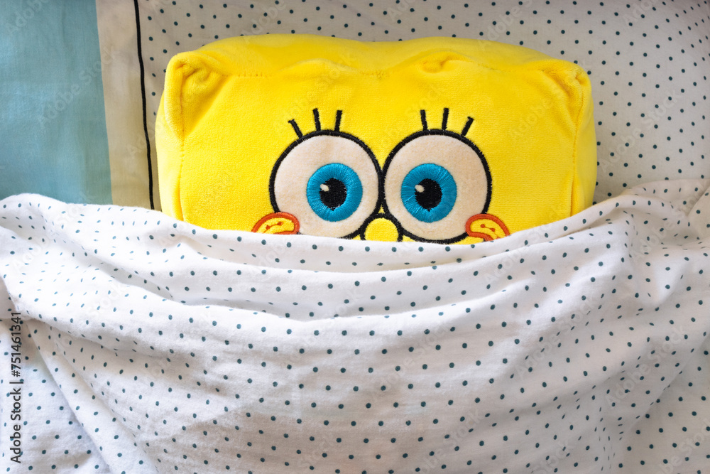 SpongeBob SquarePants peeks out from under the blanket. A plush toy ...