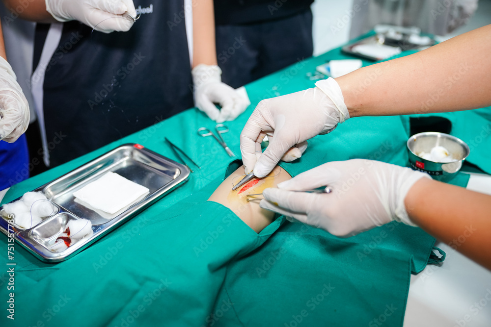 Nursing Students Practicing Surgical Suturing. A group of nursing students in scrubs perform ...