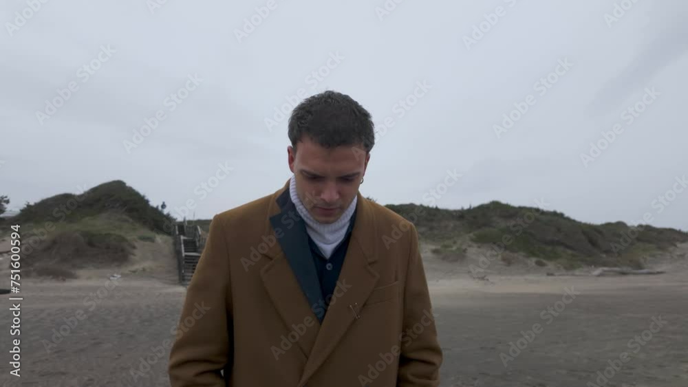 Lonely and sad well-dressed boy walks on the beach and looks at the ...