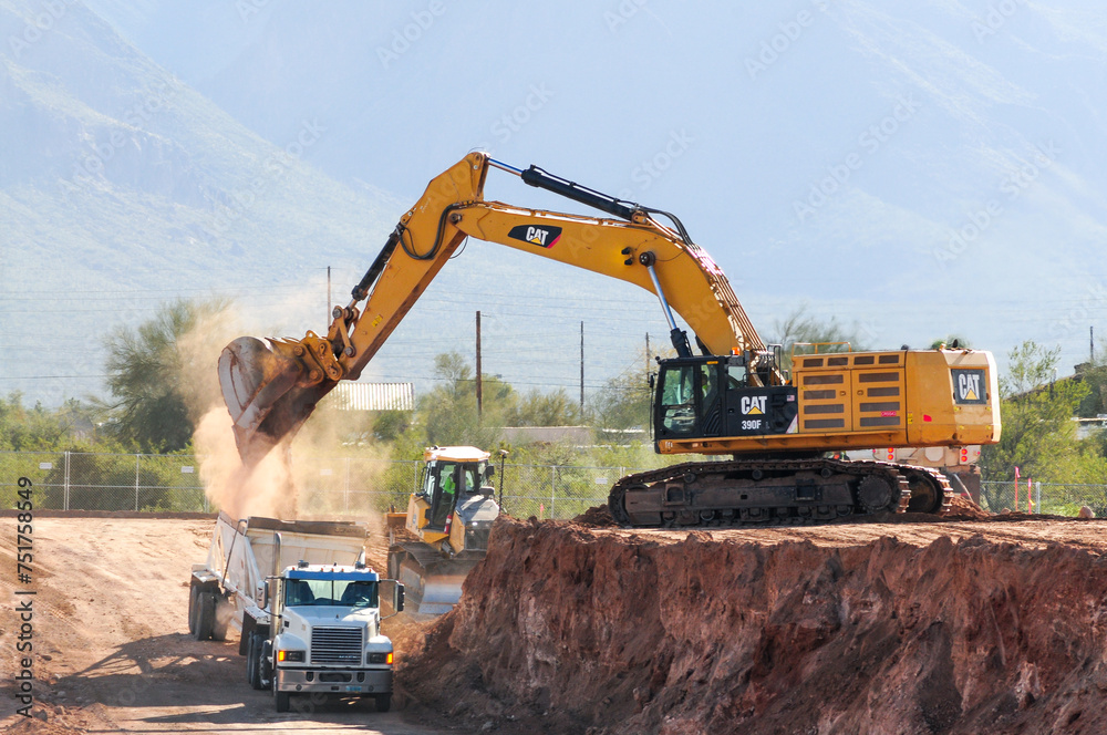 Dirt is loaded into a white dump side truck by the operator of a large ...