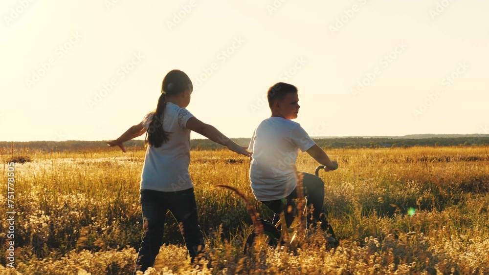 happy girl runs catching up with boy, child boy rides bicycle, son ...