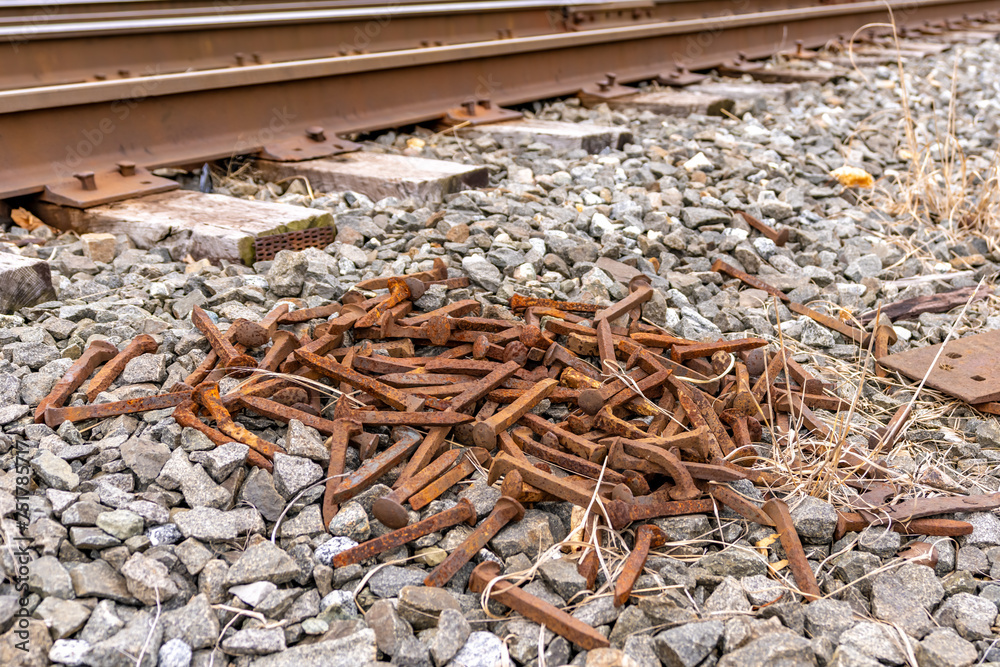 Pile of rusty railroad spikes on crushed stone next to railroad tracks ...