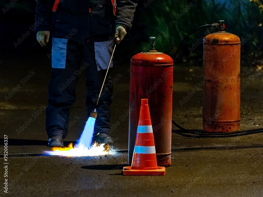 The flame of a gas burner in a selective focus during patching the road ...