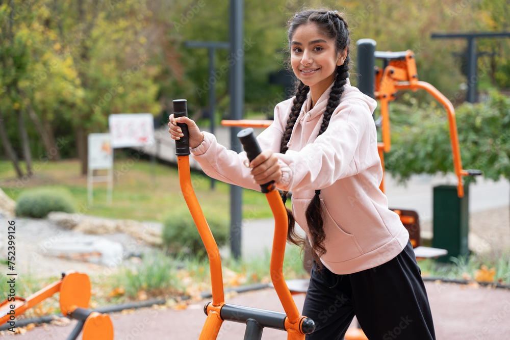 Young indian woman exercising on orbitrek machine at urban sports ...