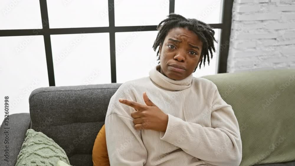 Worried young black woman with dreadlocks, nervously pointing at a ...