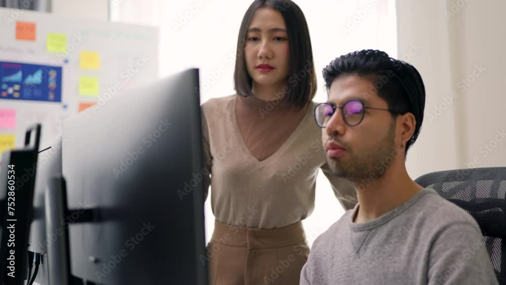 A focused male programmer and his female colleague collaborate on ...