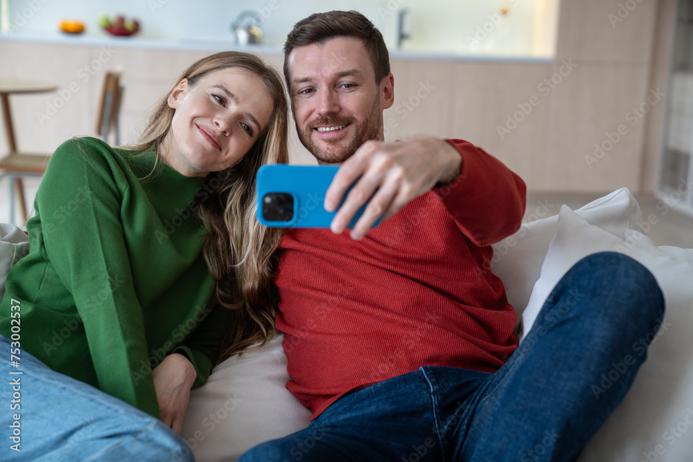 Guy and girlfriend sit comfortably on soft sofa take joint selfies ...