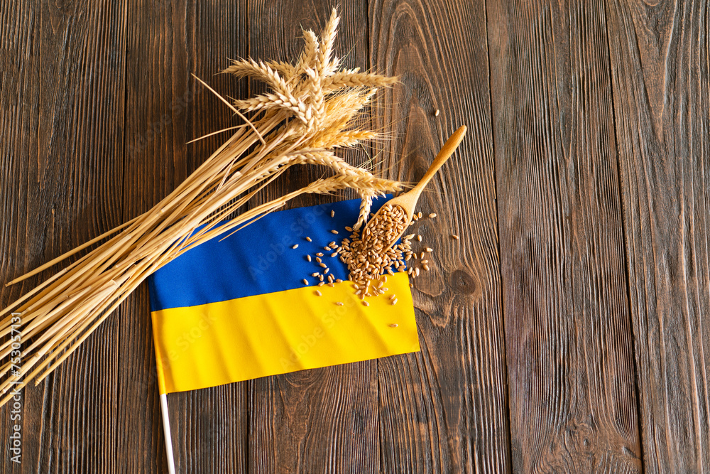 Wheat grains with yellow and blue Ukrainian flag on wooden background ...