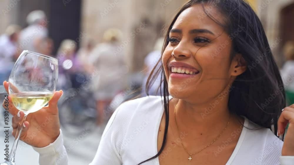 Young hispanic woman drinking wine outside in cafe patio while ...