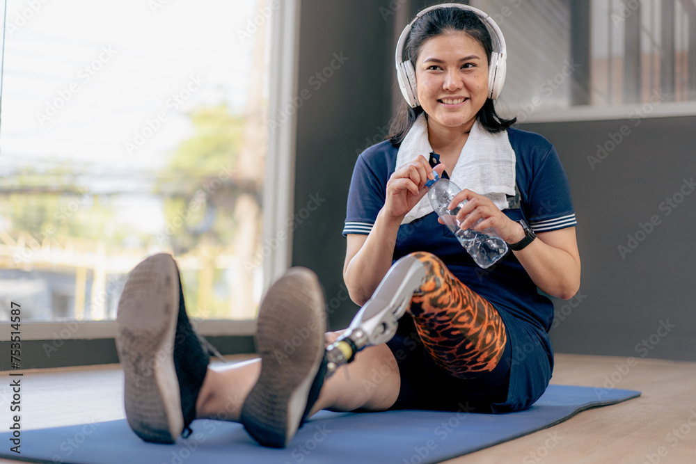 Prosthetic leg amputee woman sit relaxing in gym. Asian female with ...