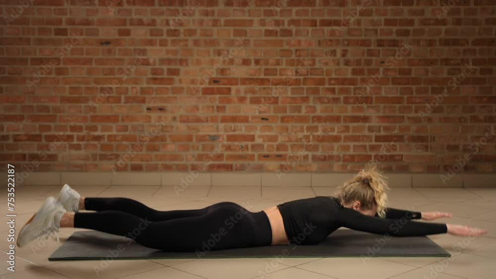 This athlete in a black outfit extends into a superman pose on the mat ...