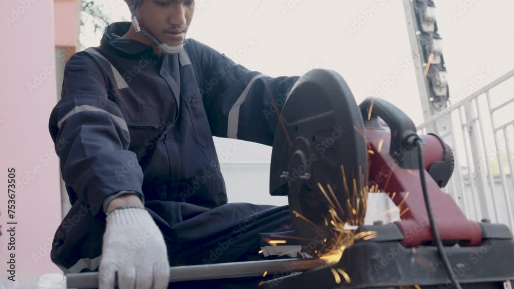 Close up Asian worker wearing a safety suit uses a steel cutting ...