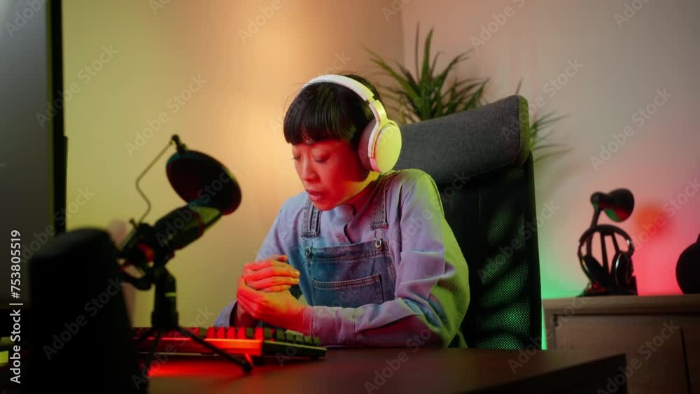 An Asian woman gamer is sitting overtime while live stream gaming ...
