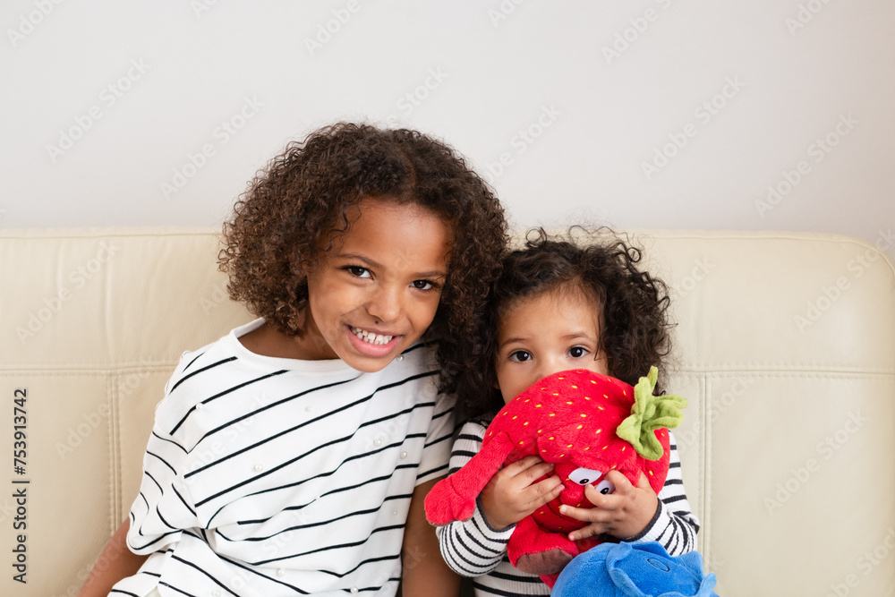 Two smiling mixed race siblings embracing, the older with a striped ...