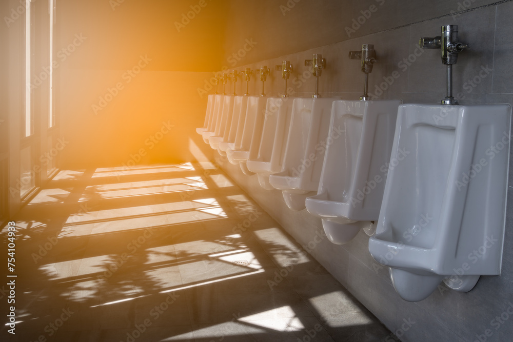 Group of white male urinals in clean public toilet with sun light and ...